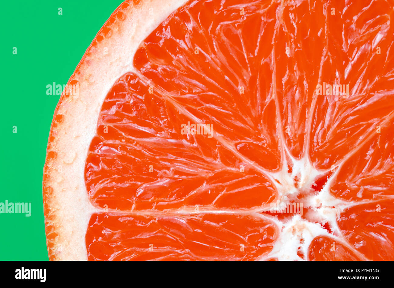 Top view of an one grapefruit slice on bright background in green color ...