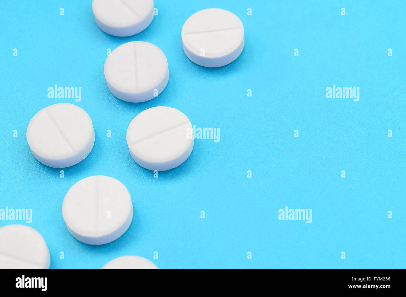 A few white tablets lie on a bright blue background surface. Background ...