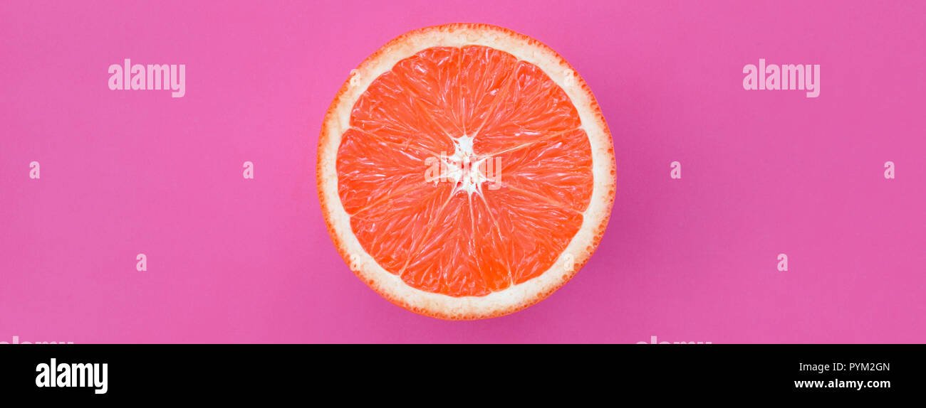 Top view of an one grapefruit slice on bright background in purple ...