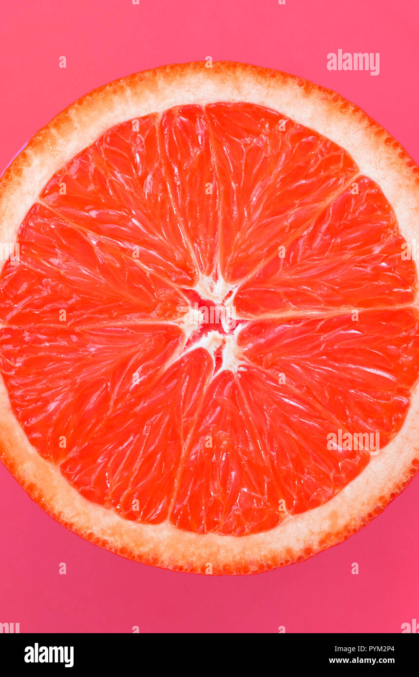 Top view of a one grapefruit slice on bright background in light pink ...