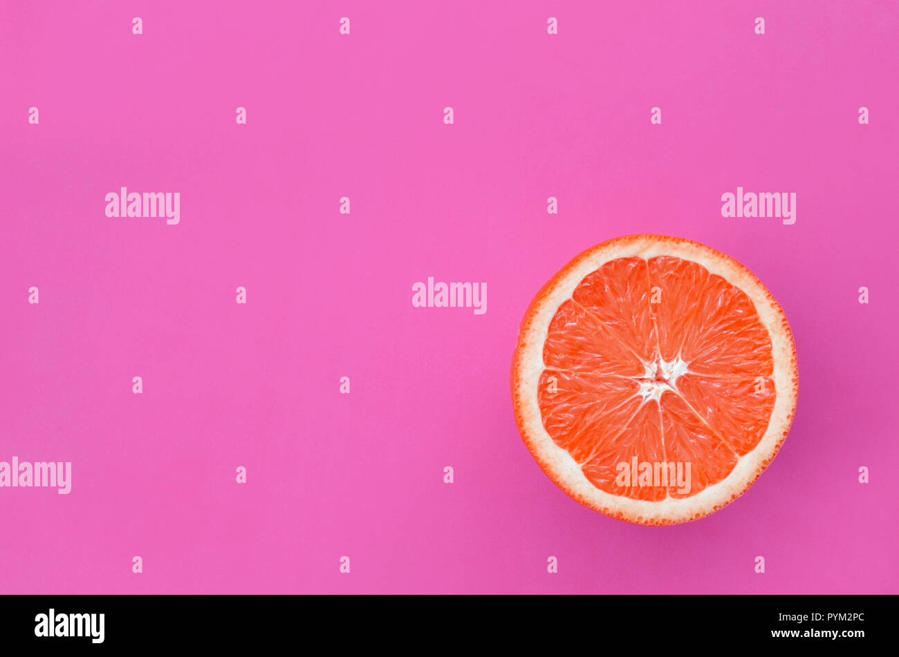 Top view of an one grapefruit slice on bright background in purple ...