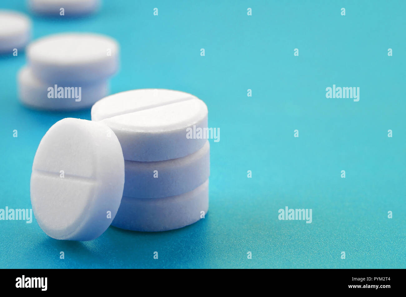 A few white tablets lie on a bright blue background surface. Background ...