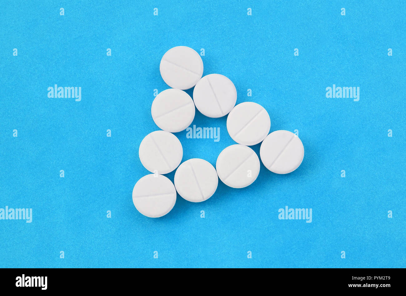 Several white tablets lie on a bright blue background in the form of an ...
