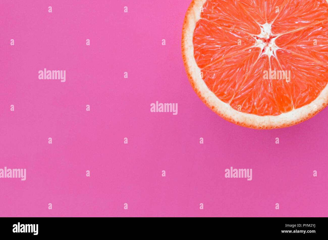 Top view of an one grapefruit slice on bright background in purple ...