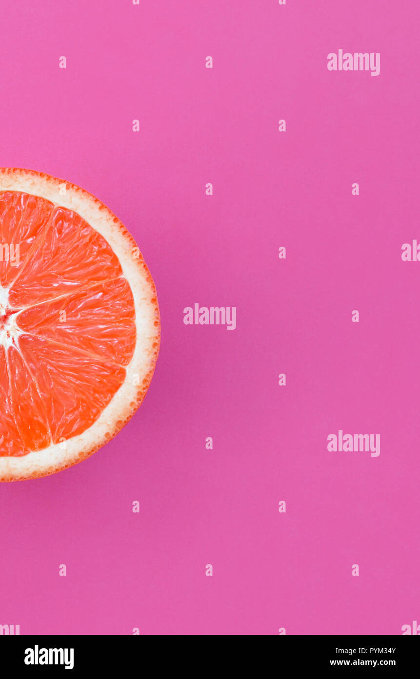 Top view of an one grapefruit slice on bright background in purple ...