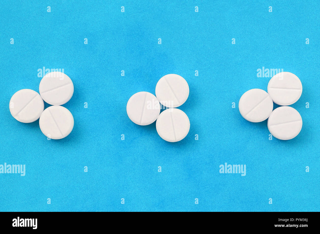 Several white tablets lie on a bright blue background in the form of ...