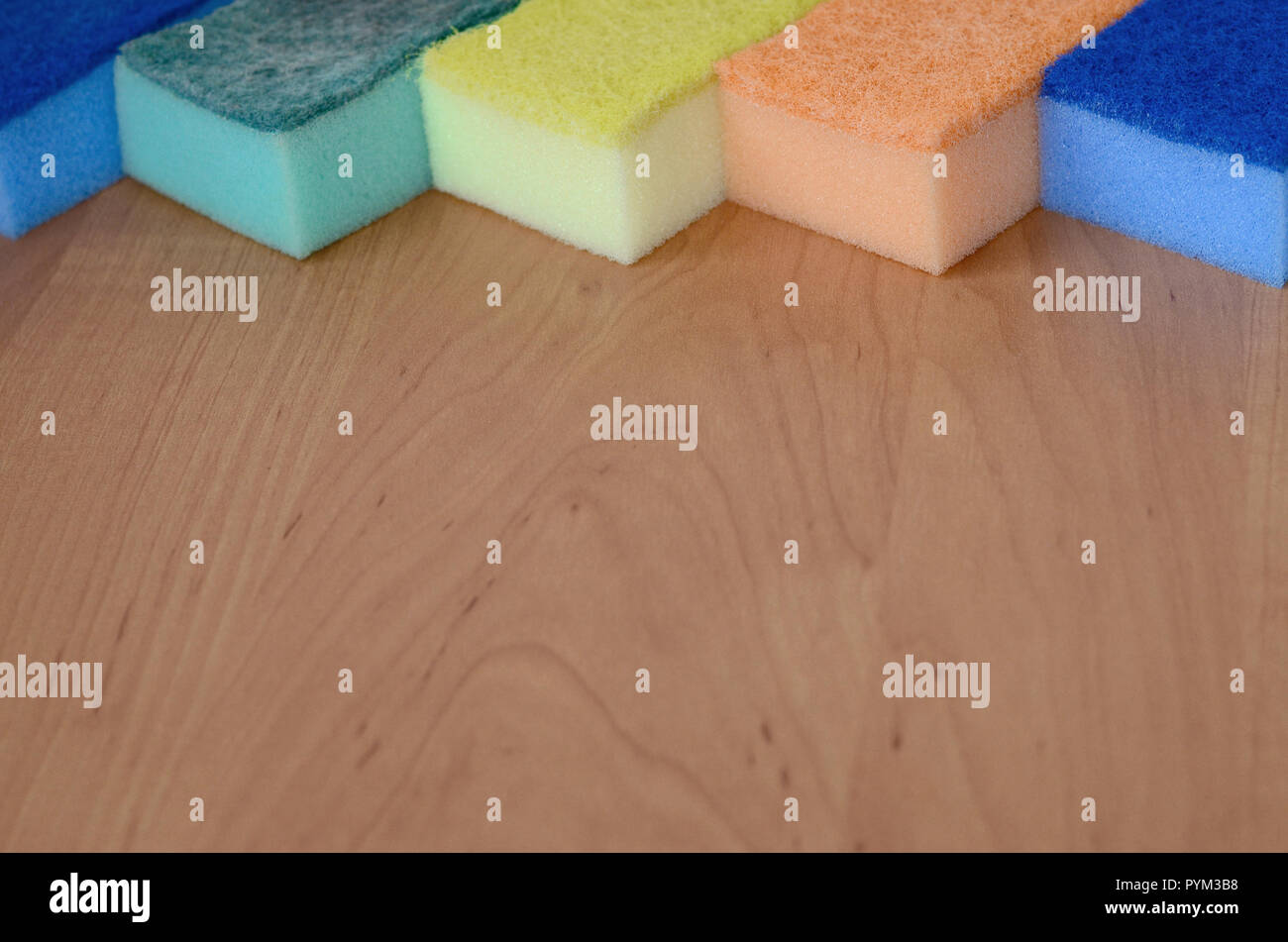 A few kitchen sponges lie on a wooden kitchen countertop. Colorful ...