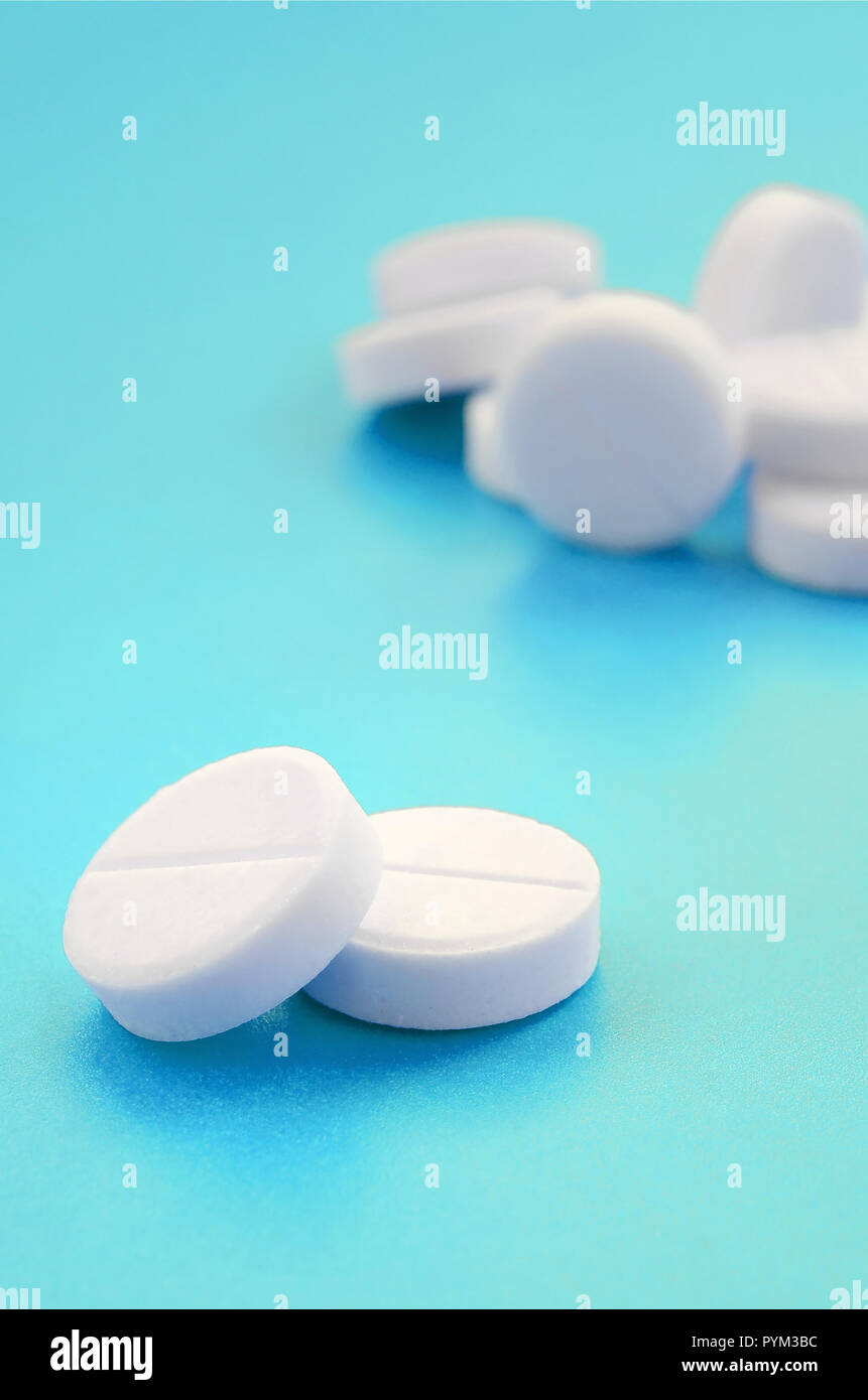 A few white tablets lie on a bright blue background surface. Background ...
