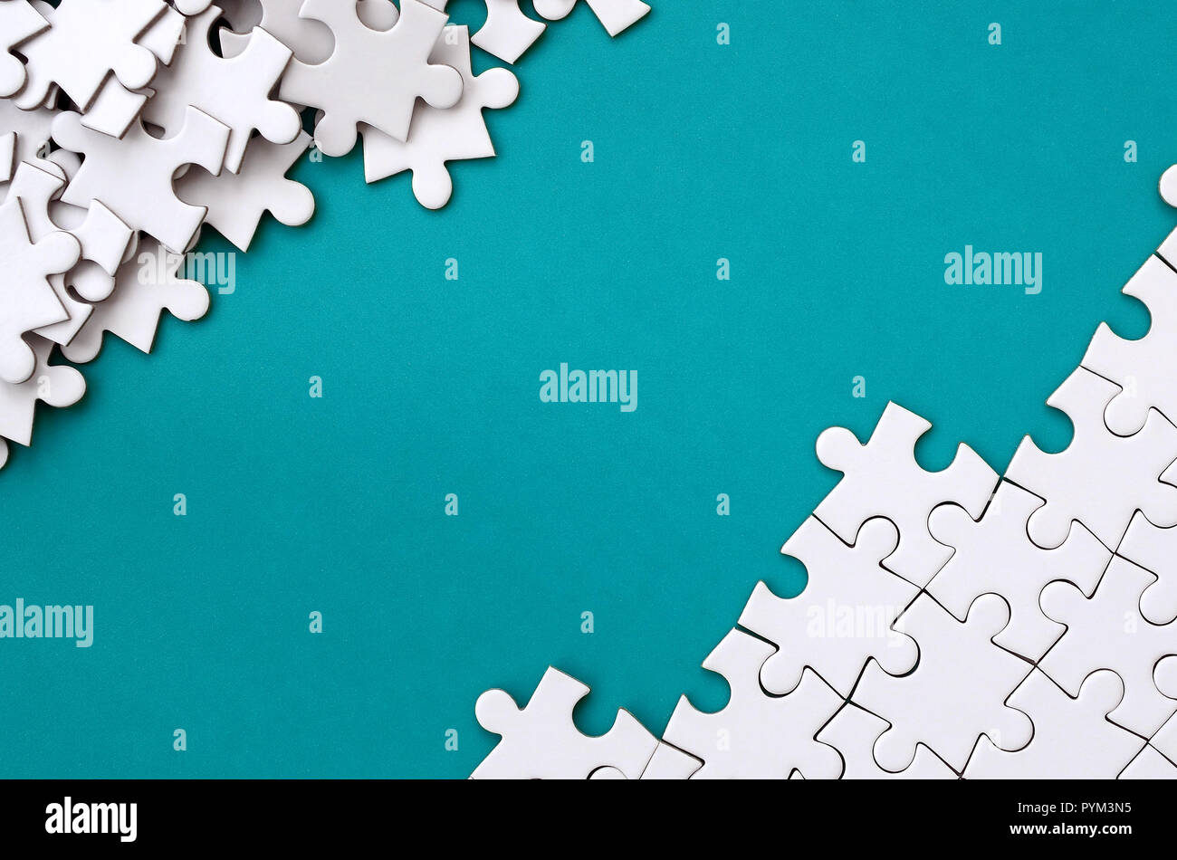 Fragment of a folded white jigsaw puzzle and a pile of uncombed puzzle ...
