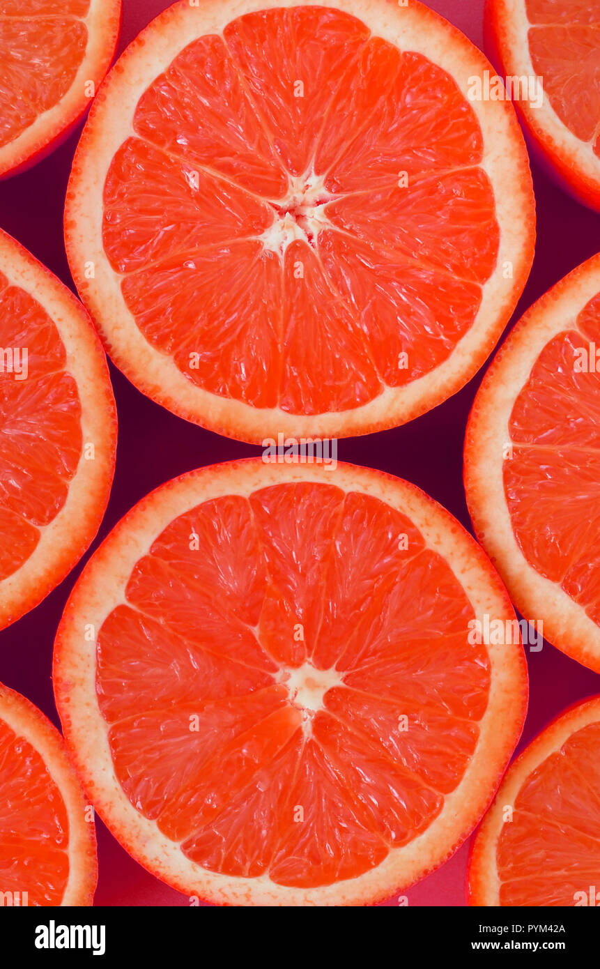 Top view of a several grapefruit slices on bright background in pink color. A saturated citrus ...