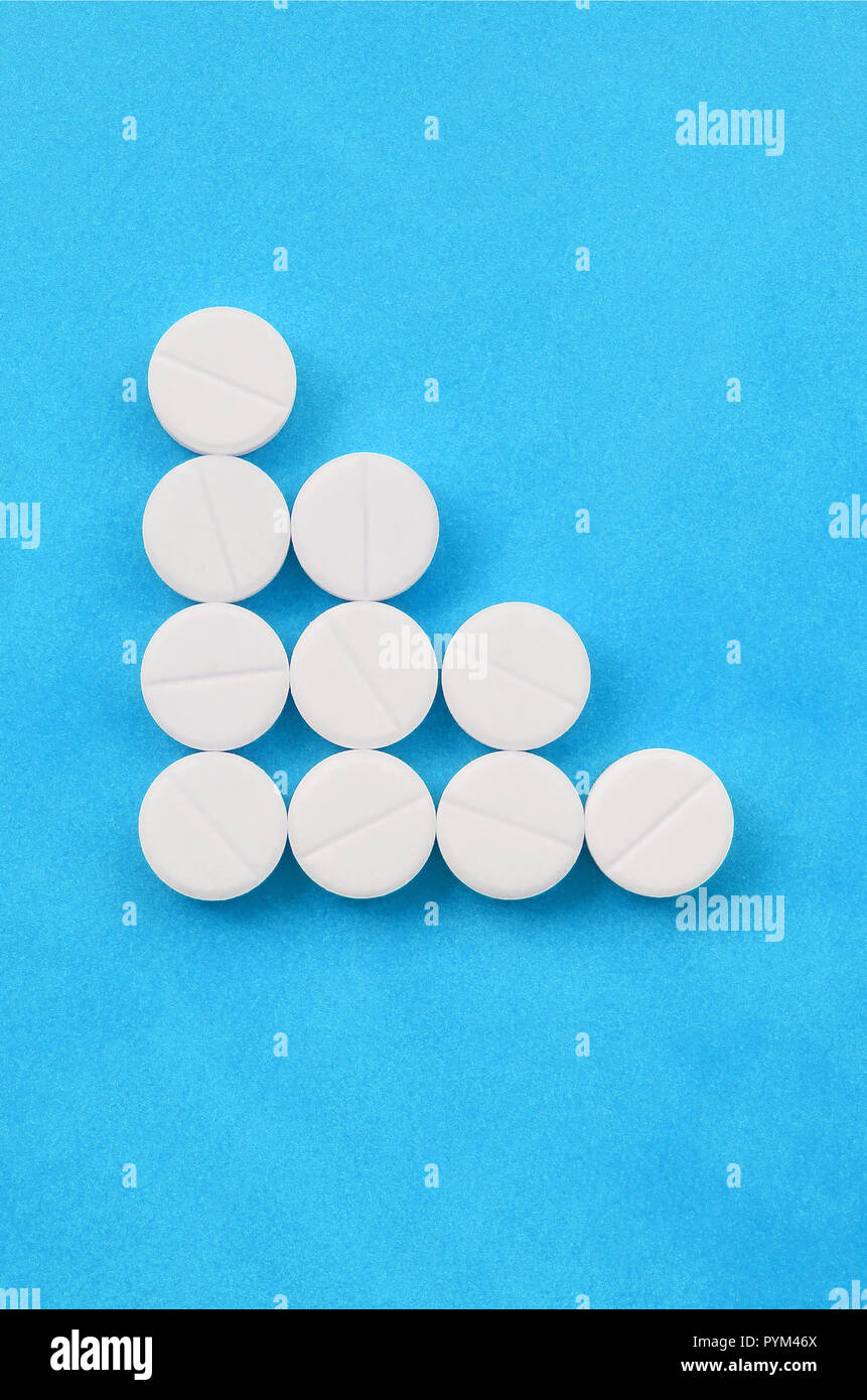Several white tablets lie on a bright blue background in the form of a ...