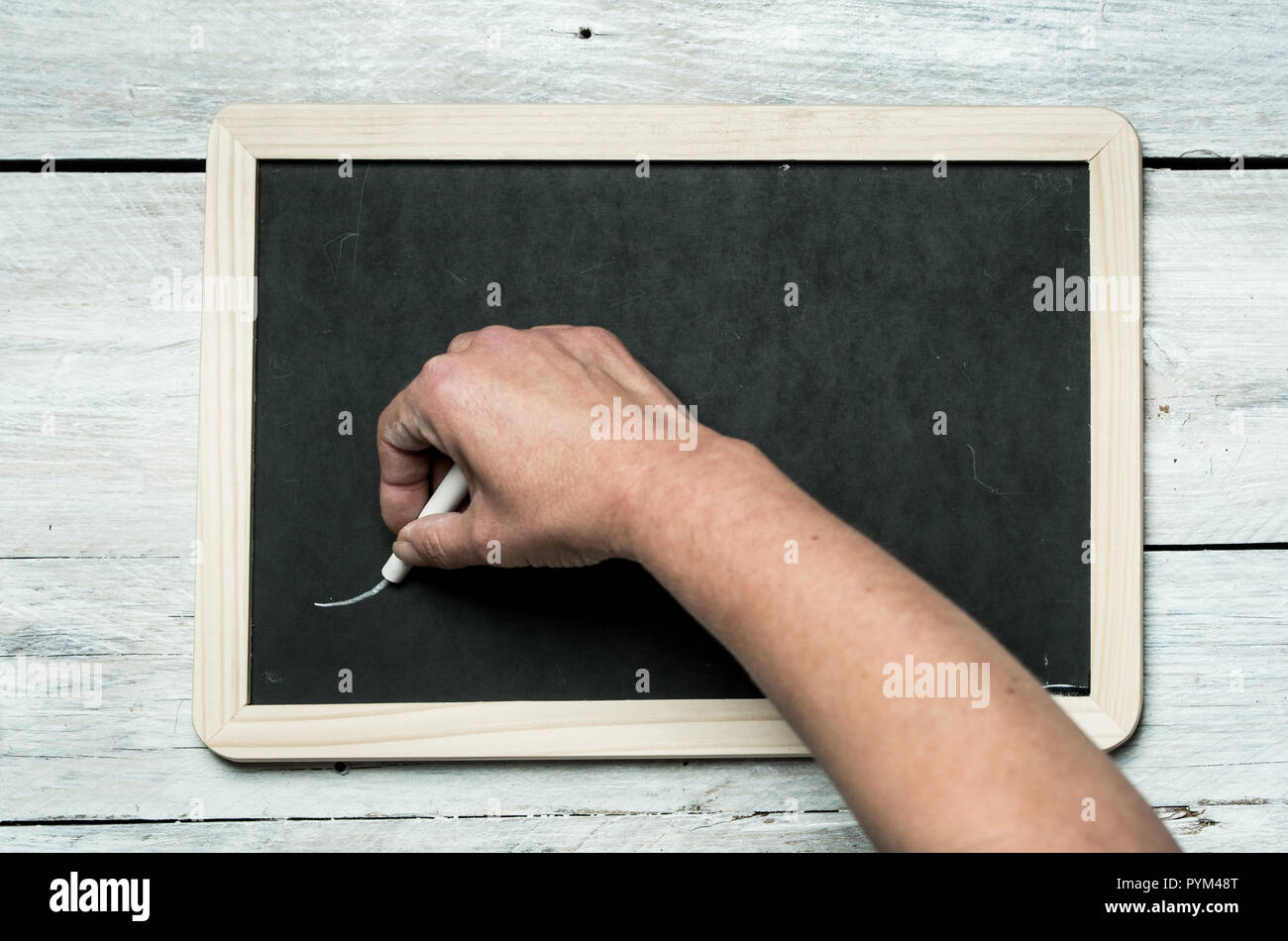 Hand with white chalk draw on the blackboard, leave a message, be ...