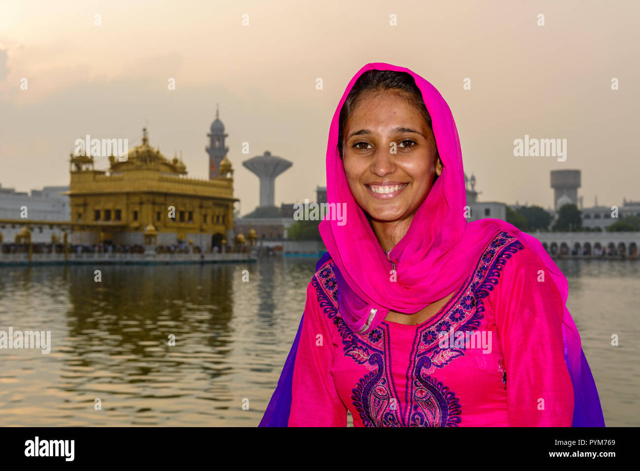A portrait of a smiling young female Sikh devotee, dressed in red ...