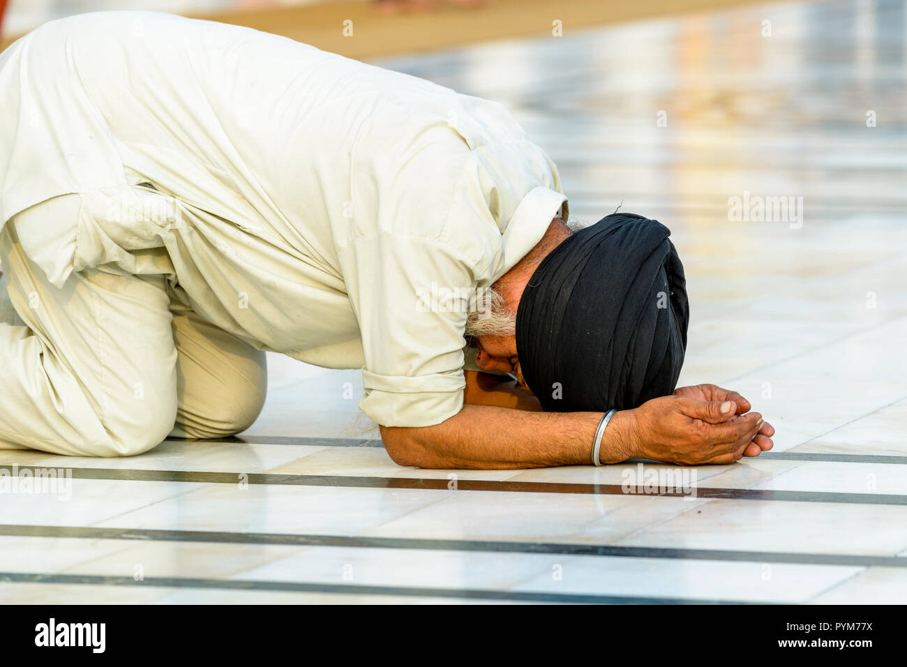 A Sikh devotee is praying at the holy pool of the Harmandir Sahib, the ...