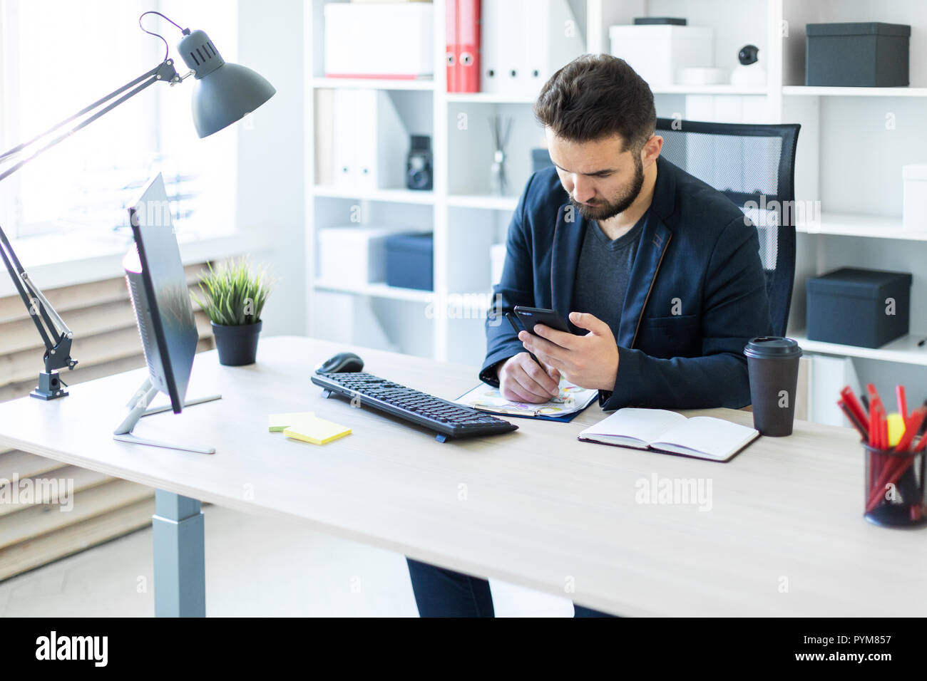 The young man works in the office at a computer Desk with documents ...