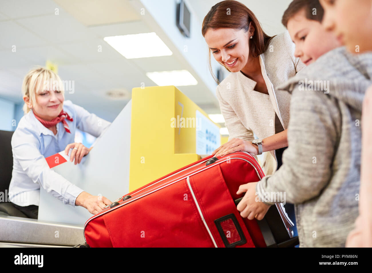 Family and children checking baggage in the airport at the check-in ...