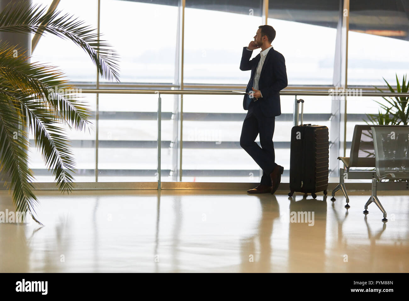 Businessman on duty talking on the mobile phone in airport waiting area ...