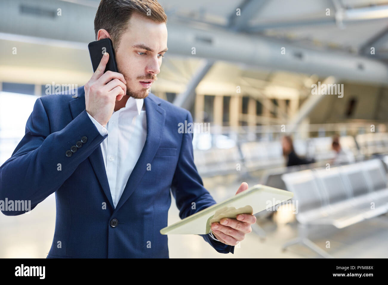 Business man using mobile phone in airport terminal is scared about a ...