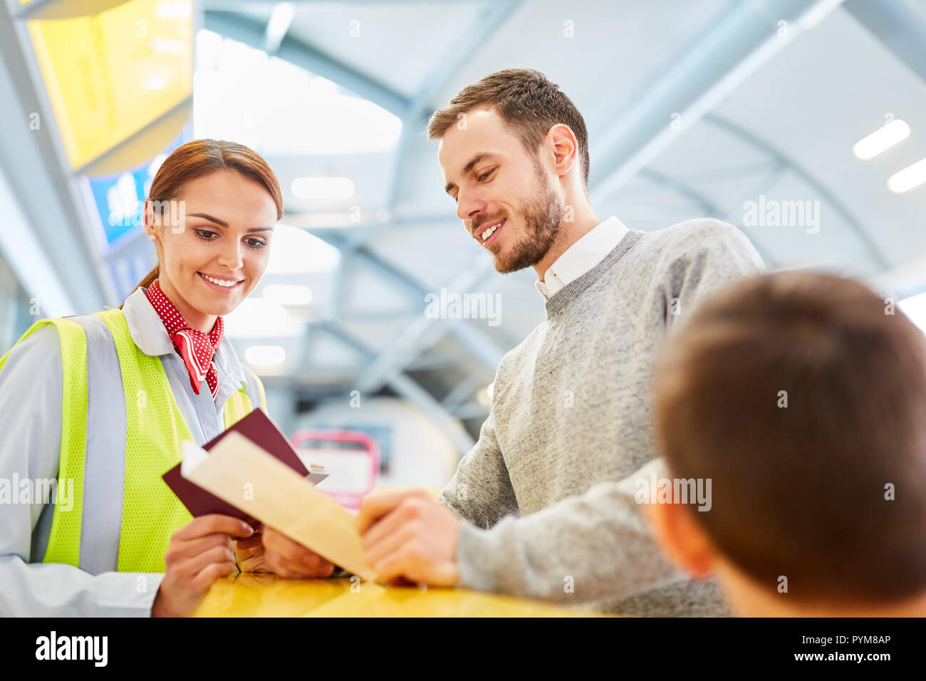 Man and service agent at check in at airport terminal looking on travel ...