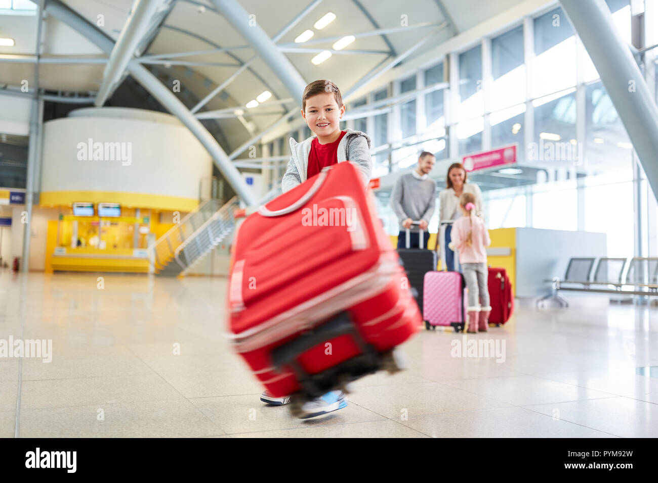 Little boy plays with a trolley in the airport terminal in the waiting ...