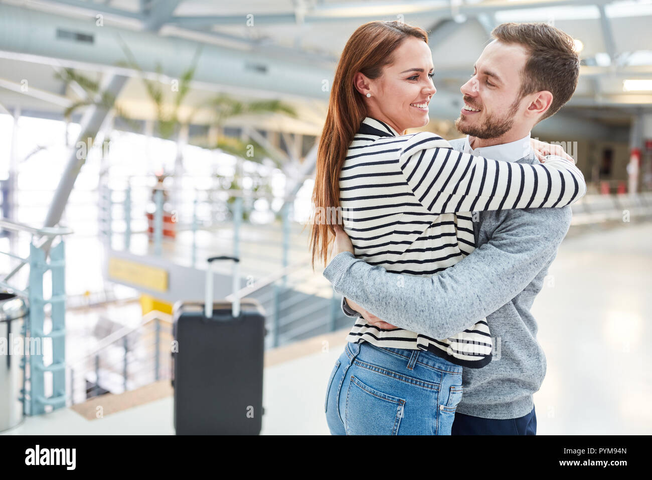 Young happy couple welcomes and hugs after the trip in the airport ...