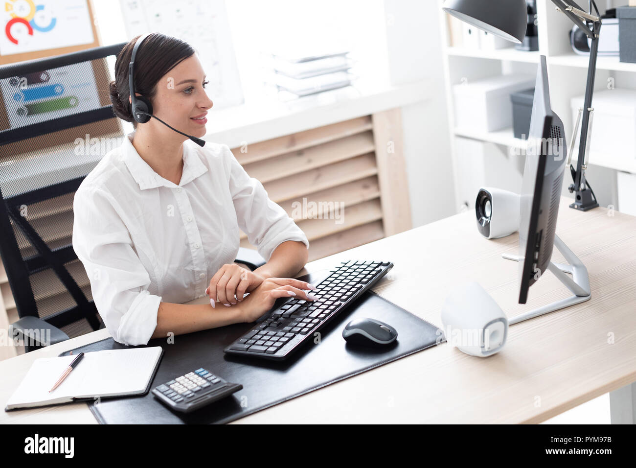 A young girl in headphones with a microphone sitting at a computer ...
