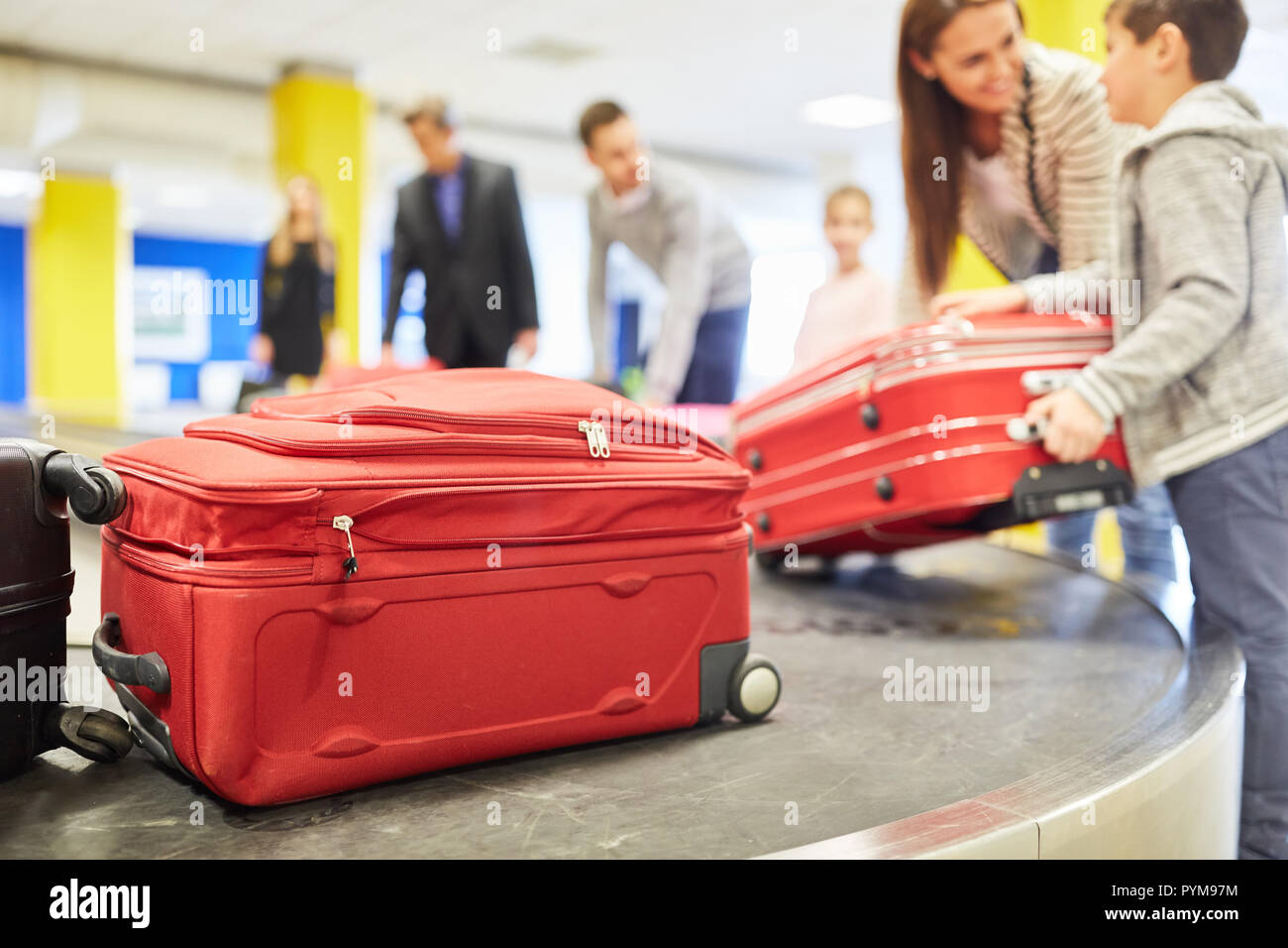 Family and travelers on the luggage belt pick up their bags in the ...