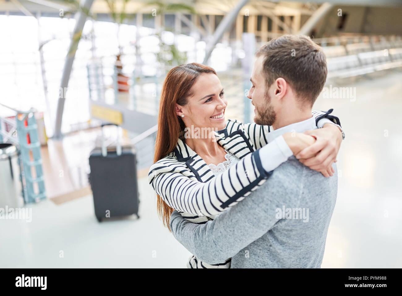 Happy couple in airport terminal hugging each other while reunion after ...