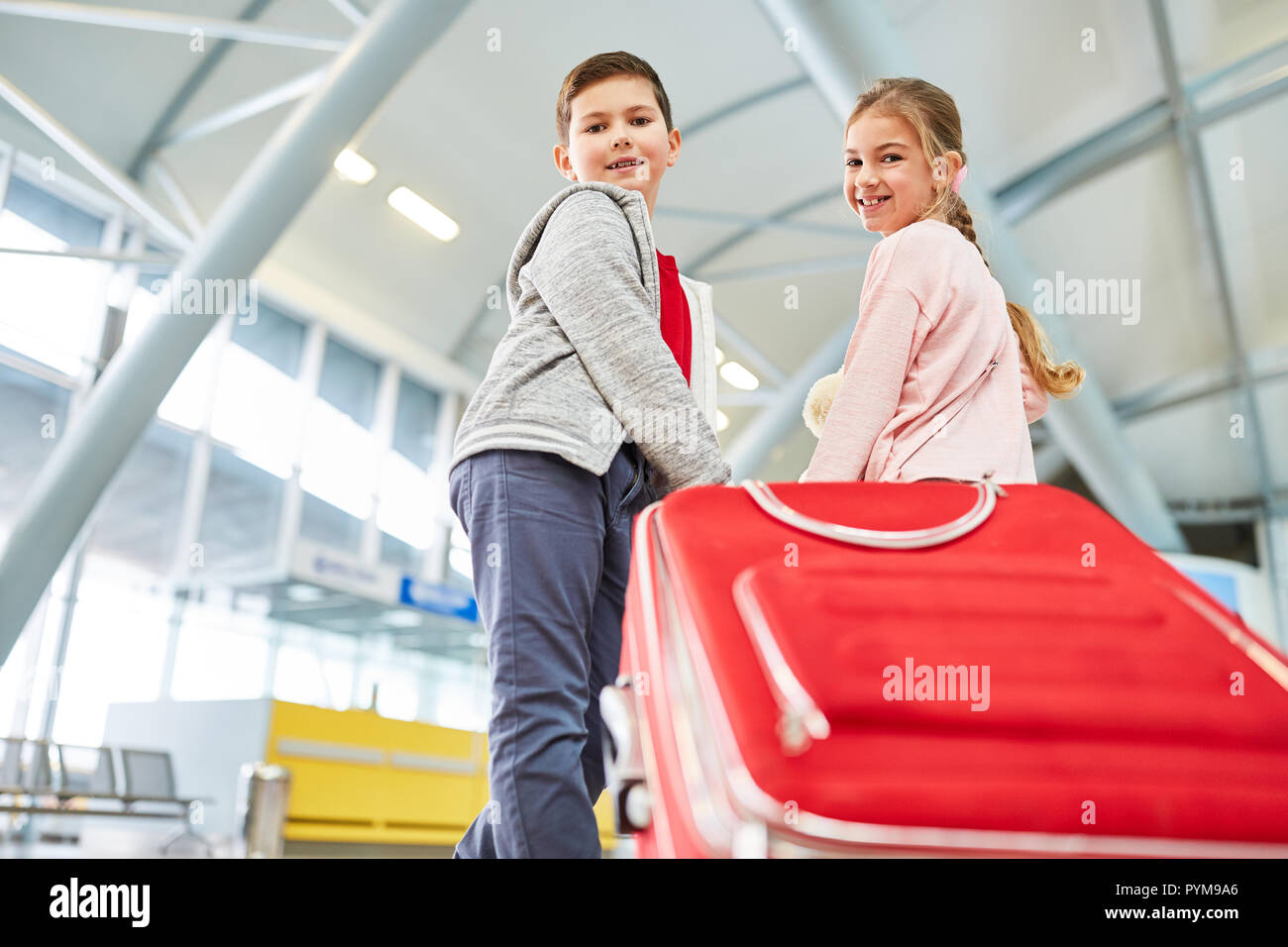 Siblings in the airport terminal with suitcase together make a plane ...