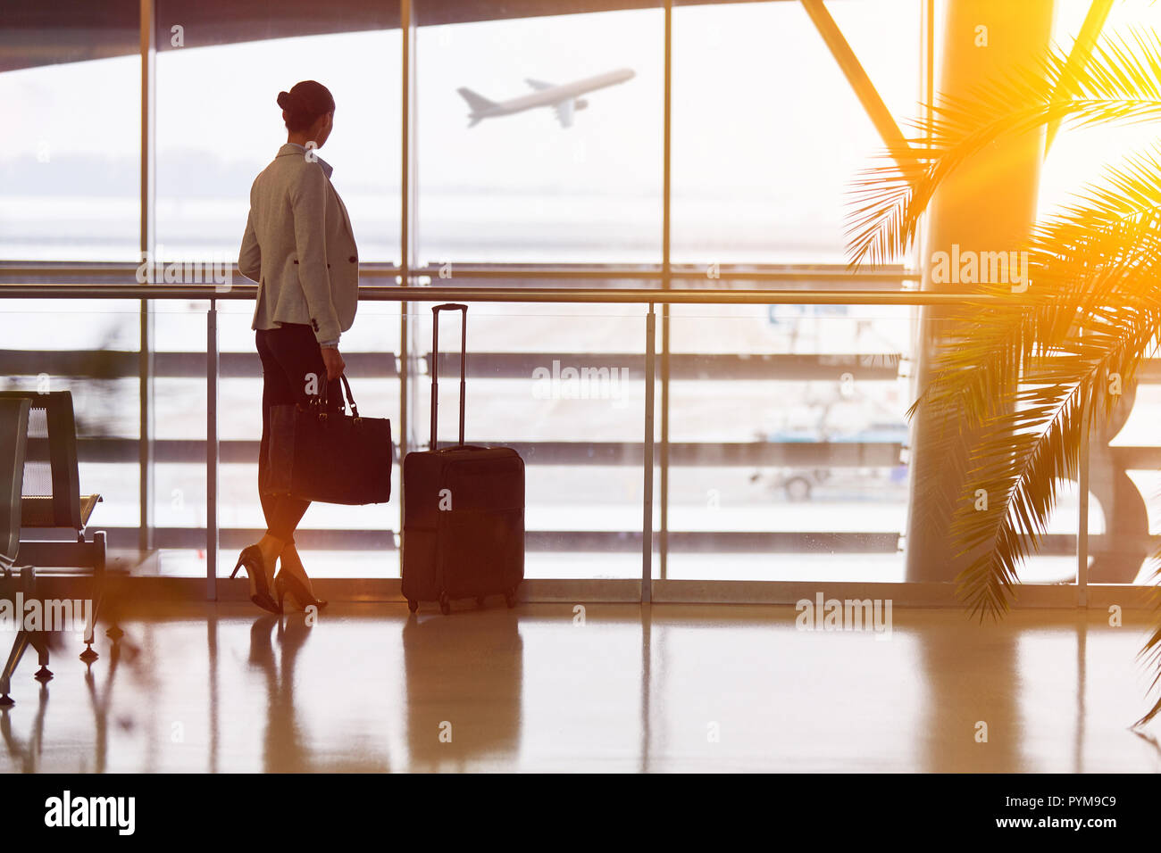 Businesswoman at the airport looks at the waiting for a plane taking ...