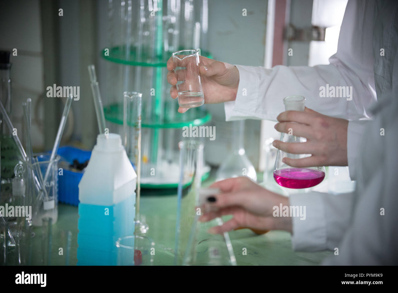 Table full of chemicals and flasks. Chemical lab. Hands holding flasks ...