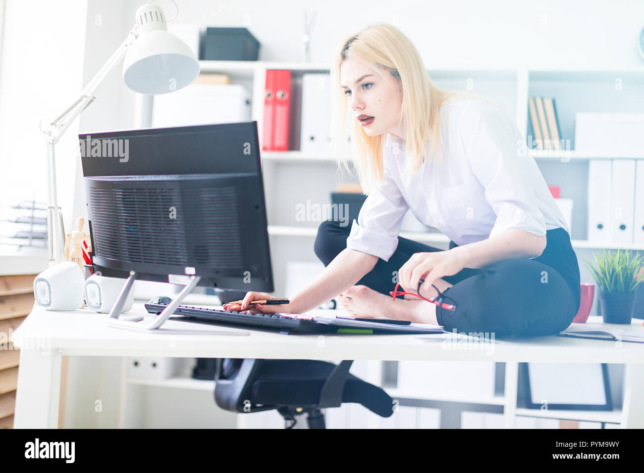 A young girl sitting on a Desk in the office and working with documents ...