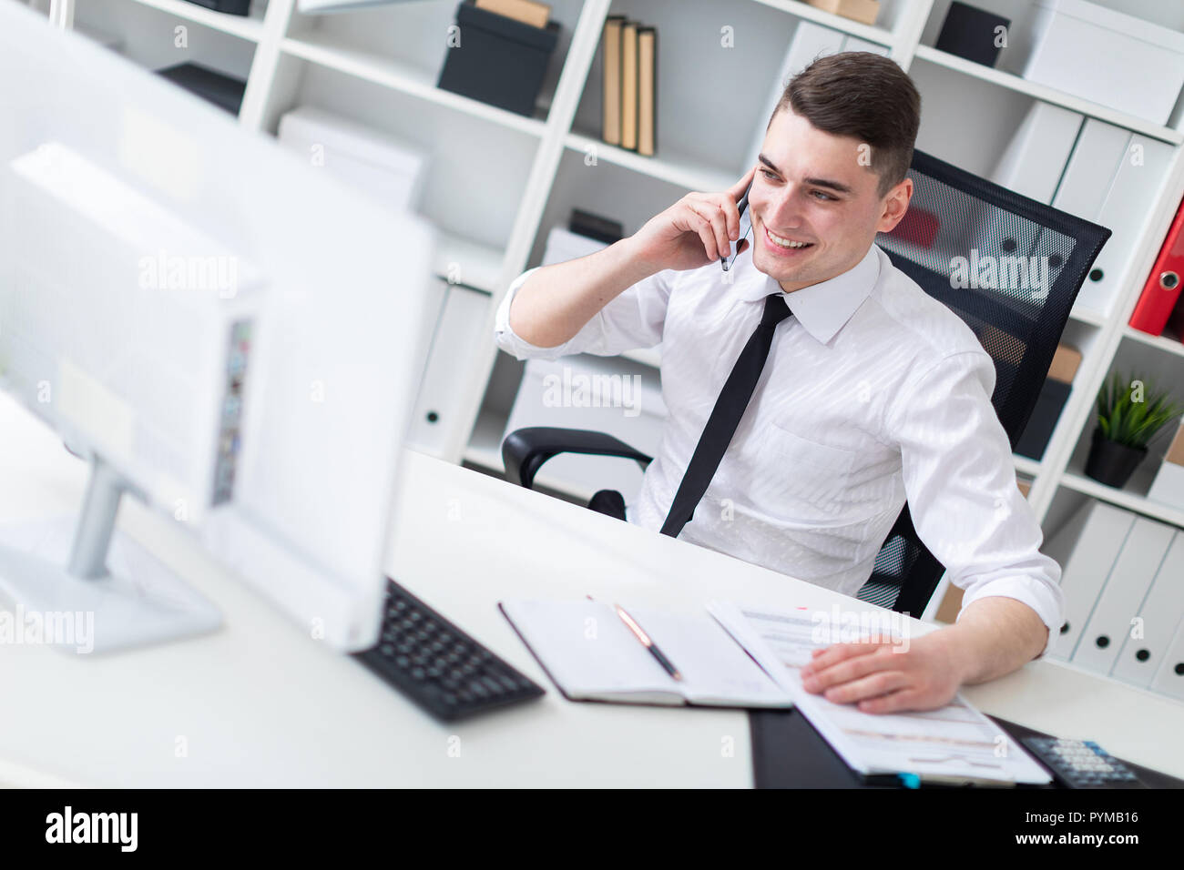 A young man sitting at a computer Desk in the office and looking at the ...