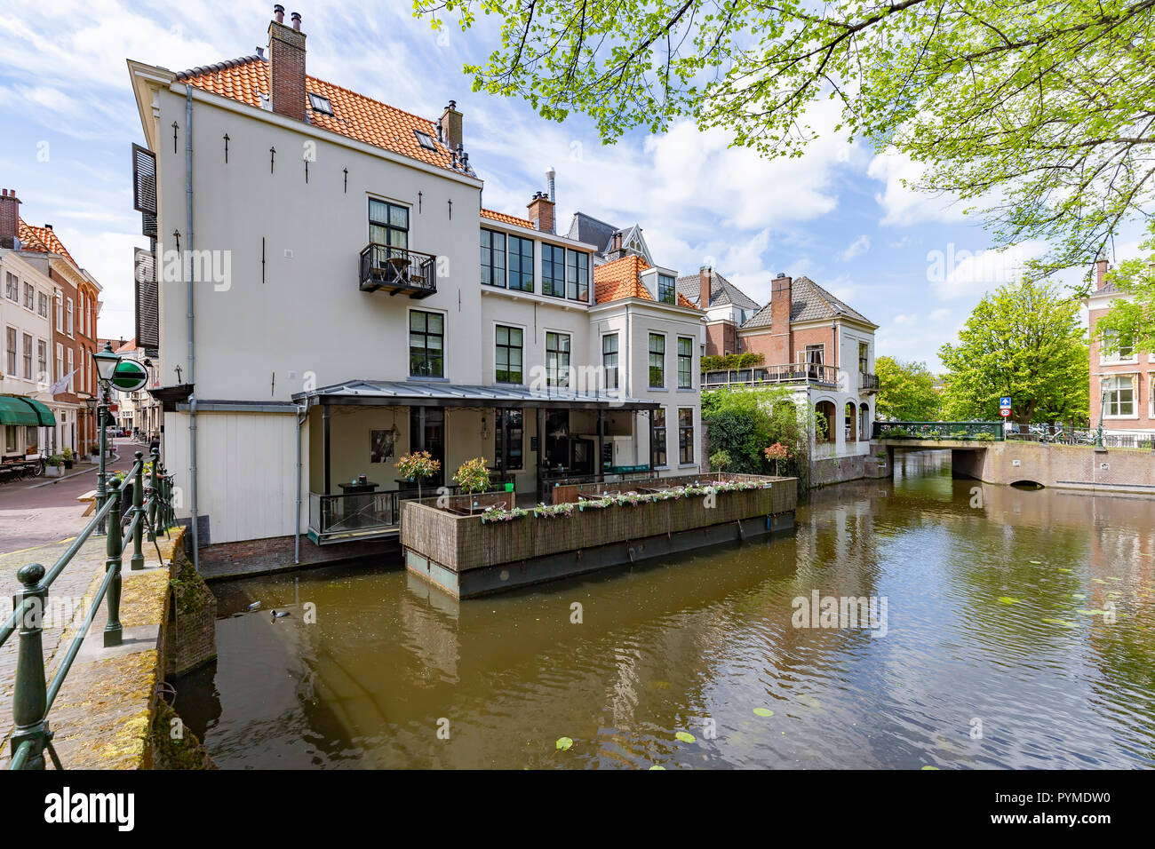 Typical Dutch cityscape with a little brick bridge over a calm canal ...