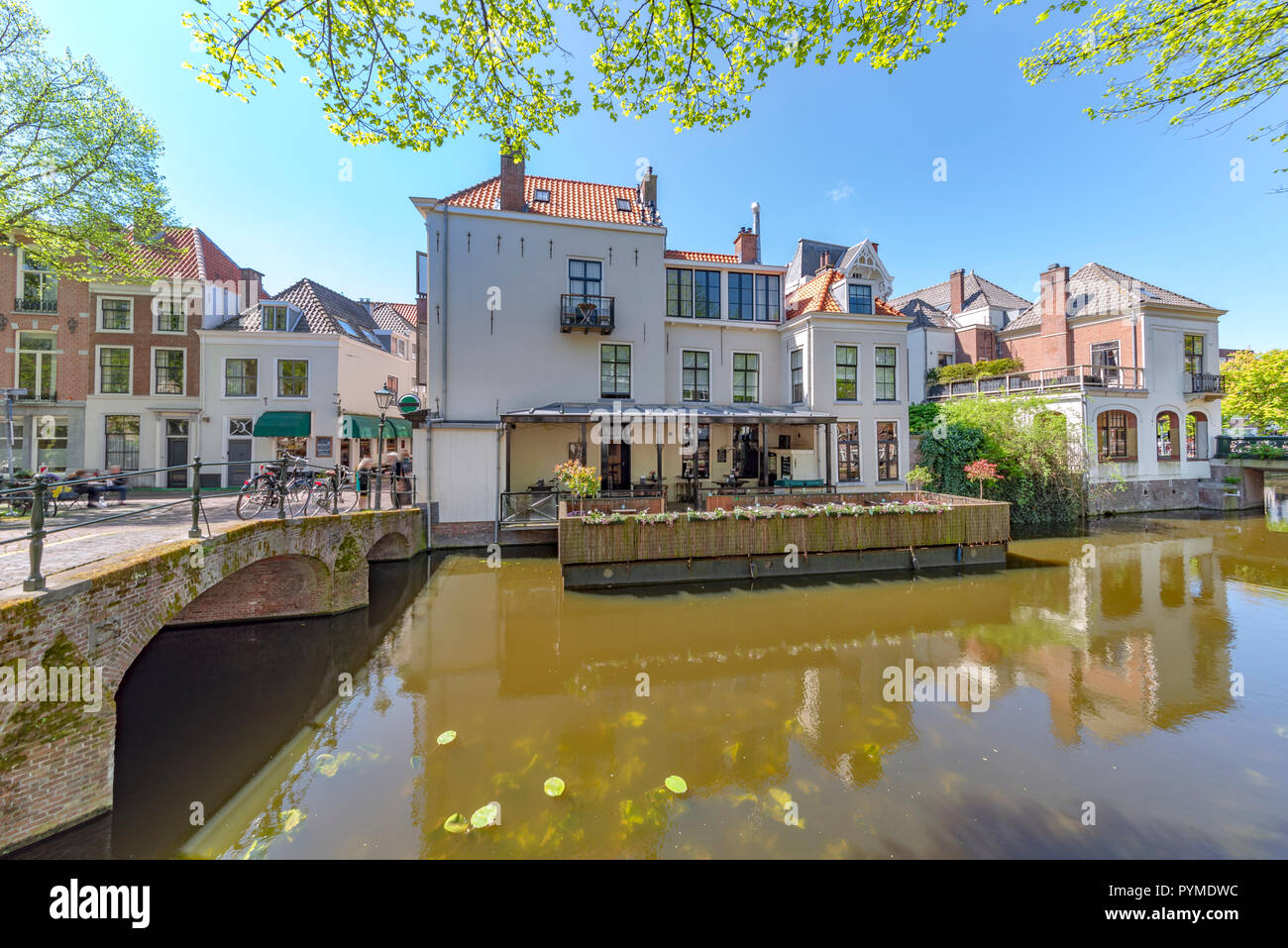 Typical Dutch cityscape with a little brick bridge over a calm canal ...