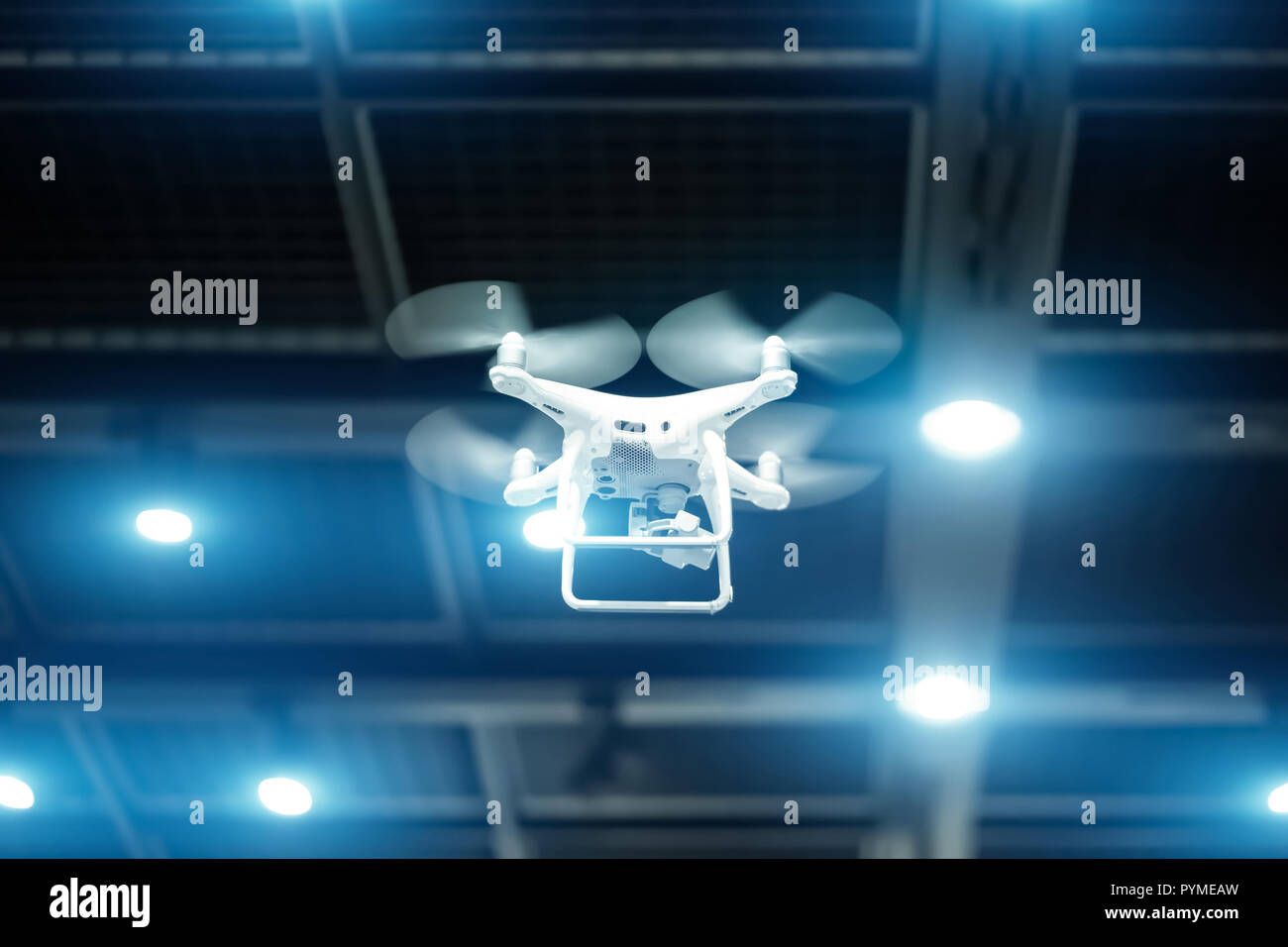 White drone in motion. Quadcopter flying inside a large warehouse Stock ...
