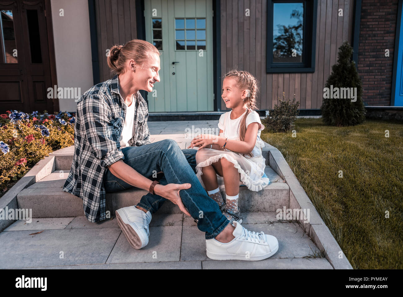 Father and daughter sitting on the porch outside house waiting for ...
