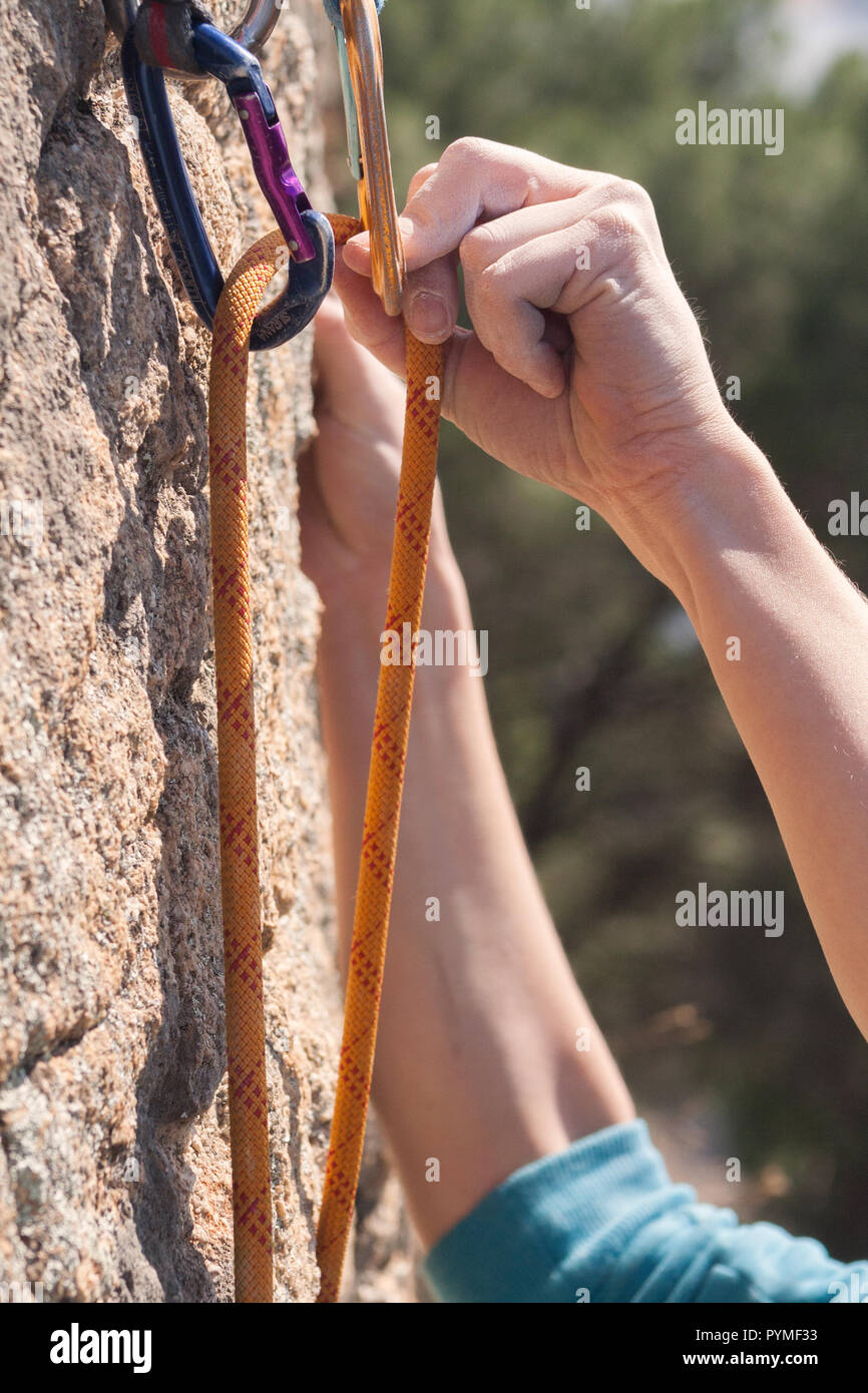 Close up of hand of a climber passing the rope through a quickdraw ...