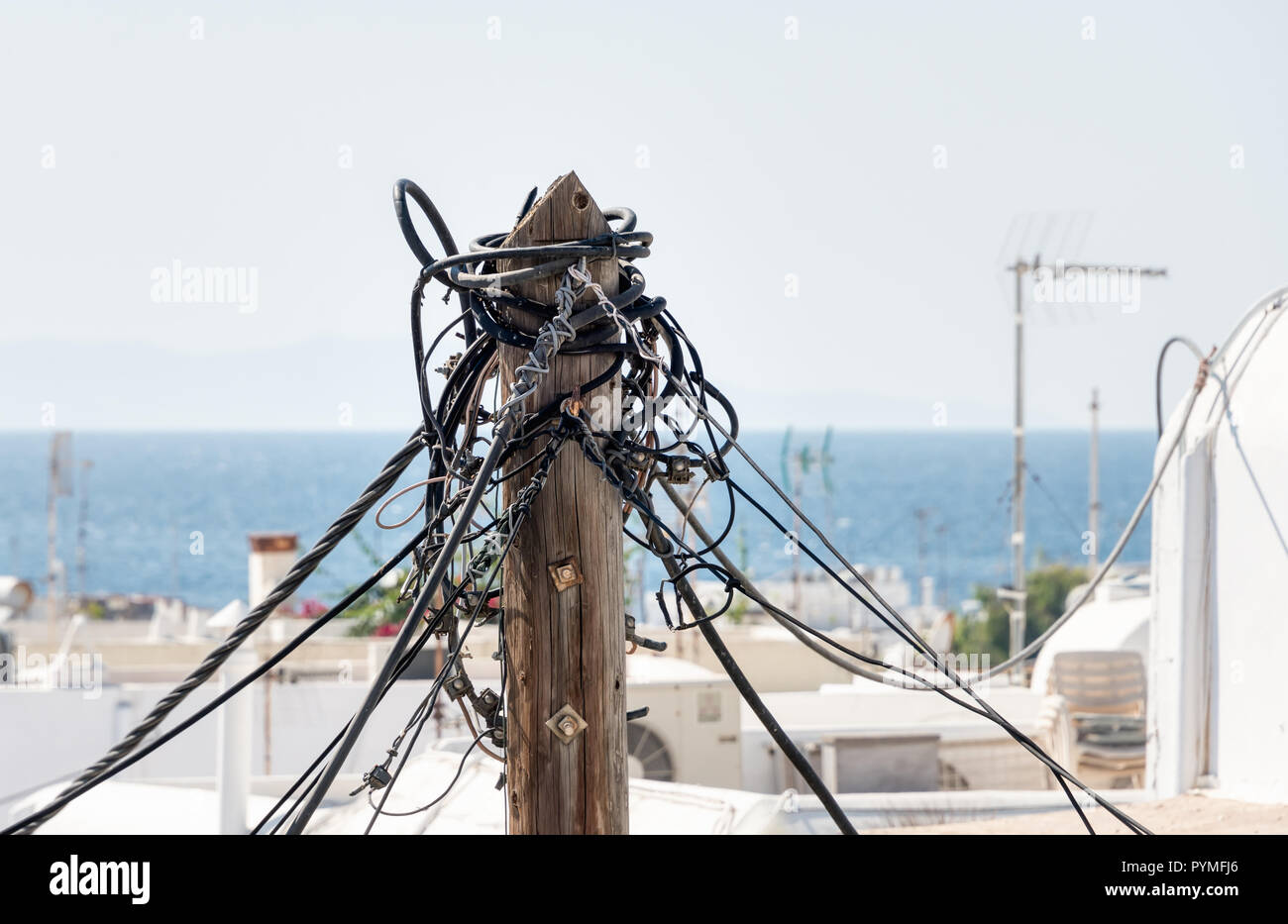 Old traditional electric distribution wood pole with a tangle of power ...