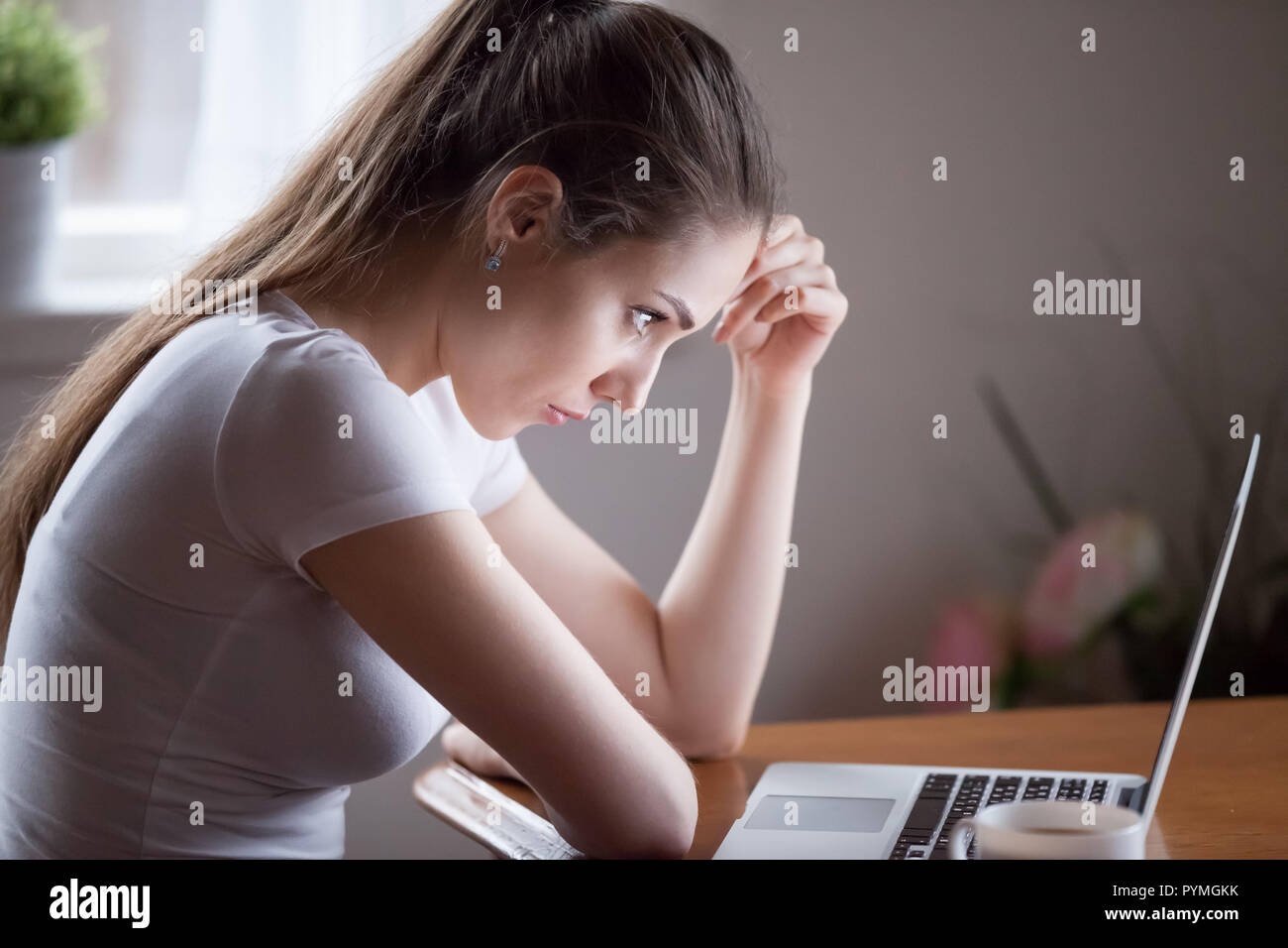 Young woman thinking looking on computer screen Stock Photo - Alamy