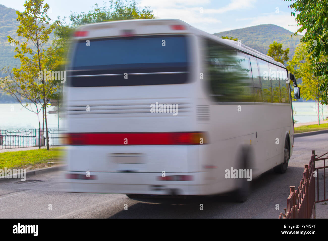 tourist bus moves along the road along the mountain lake Stock Photo ...