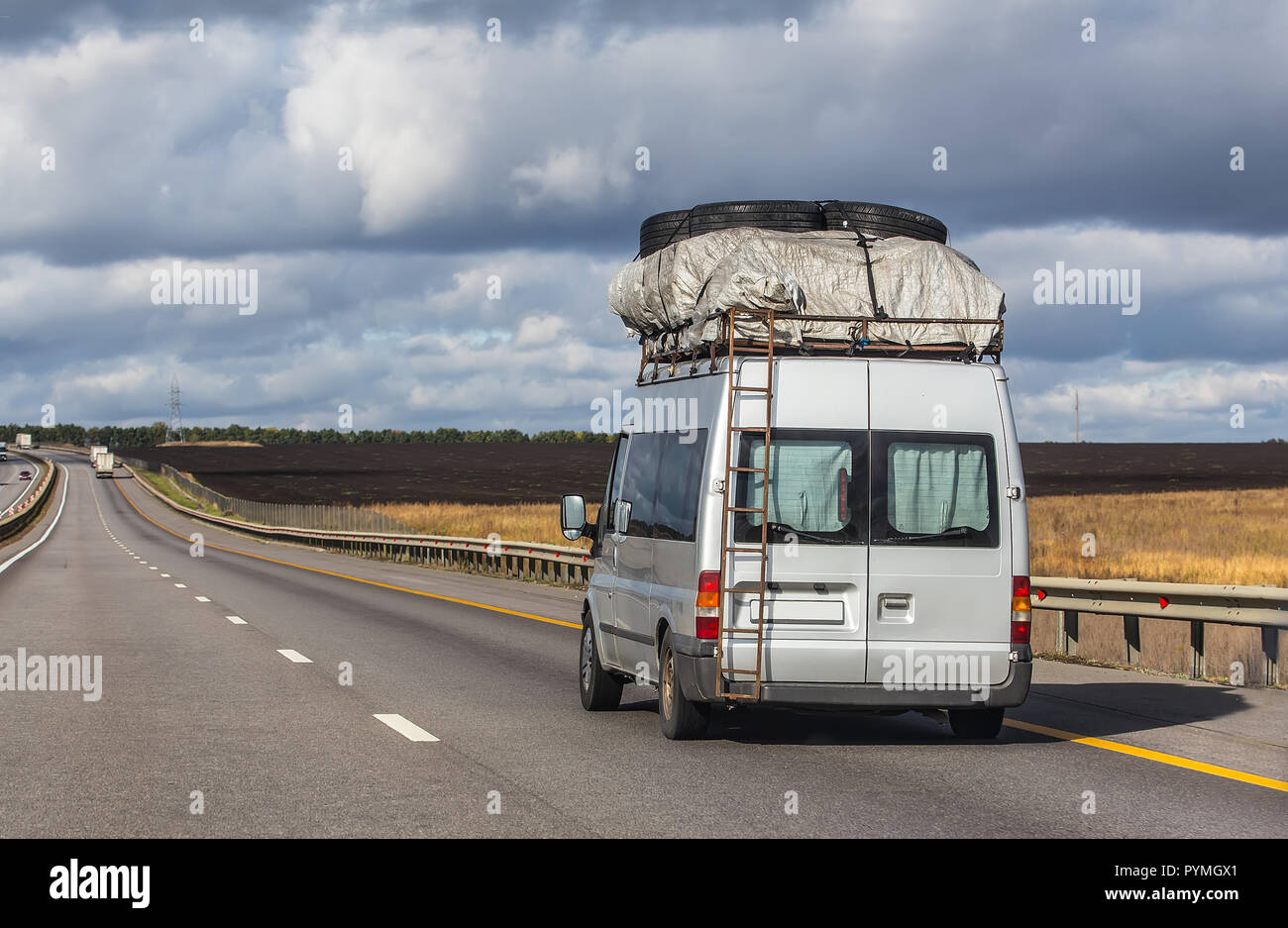 A mini bus with the trunk on top moves along the road. Back view Stock ...