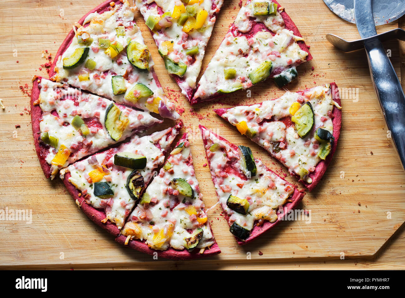 Beetroot base pizza with zucchini, smoked ham, cheese & red onion Stock Photo - Alamy