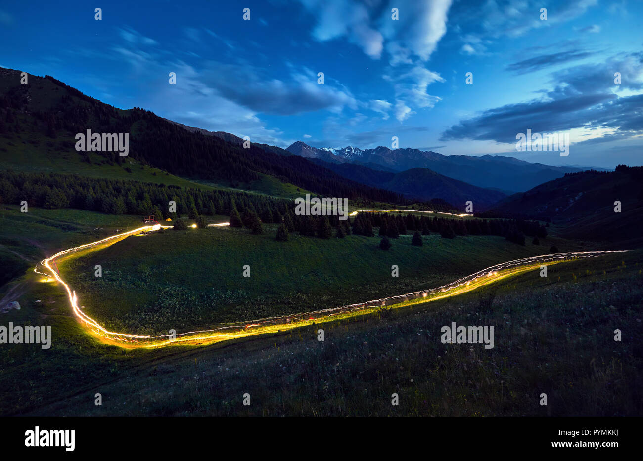 Light trace of runners led on the race in the mountains at twilight sky ...