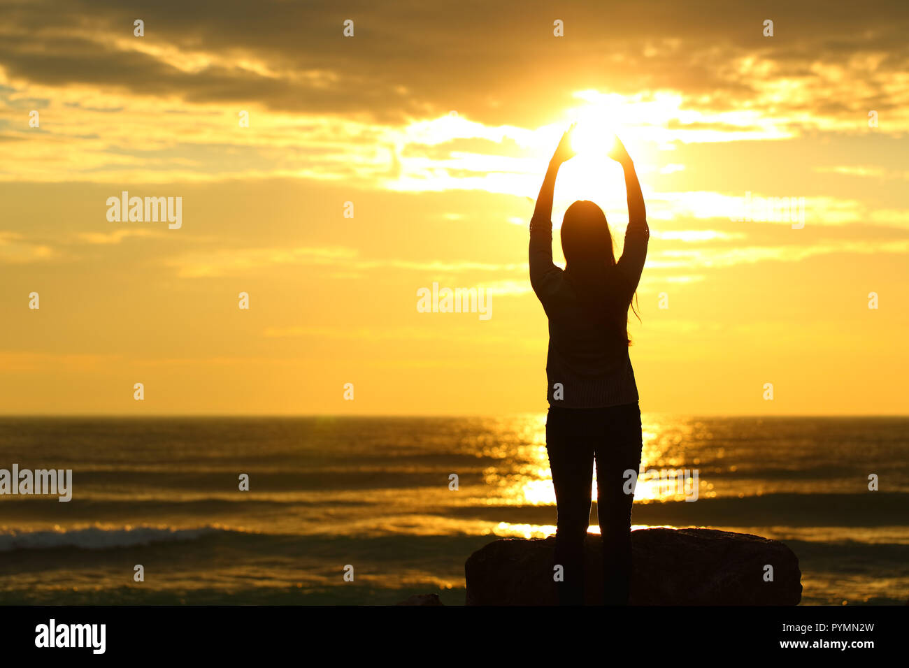 Back View Backlight Silhouette Of A Woman Reaching Sun At Sunset On The