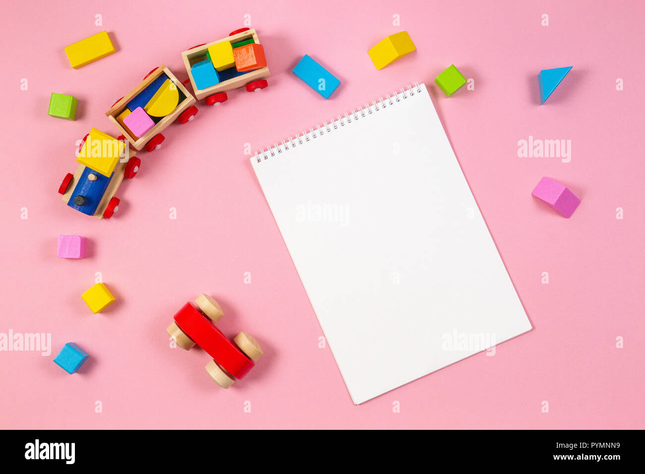 Wooden toy train, red car, colorful cubes and white blank open notebook ...
