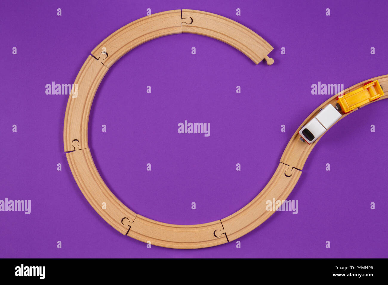 Toy train and wooden rails on purple violet background Stock Photo - Alamy