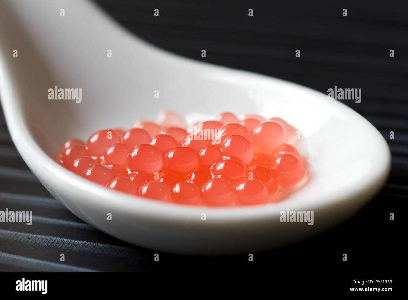 Molecular melon caviar balls on spoon Stock Photo - Alamy