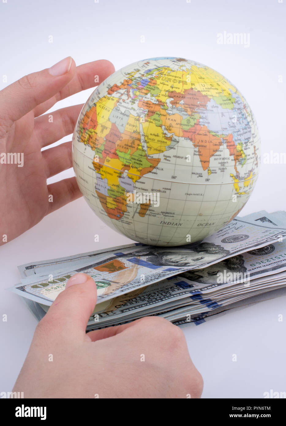 Human hand holding a model globe by the side of aAmerican dollar ...