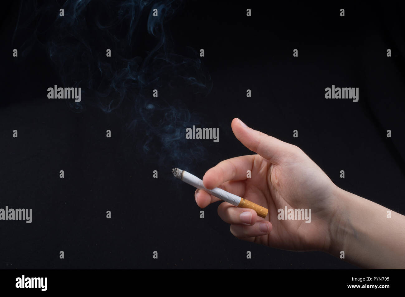 Hand is holding smoking cigarette with smoke around Stock Photo - Alamy